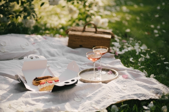 Beautiful summer picnic with fresh sweet eclairs and champagne in a ...