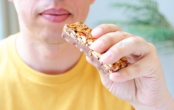 Man eating protein bar on a gray background close-up. Stock Photo by ...