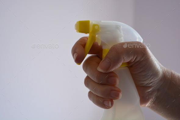 Gloved hand holding a plastic spray bottle for liquids. Generic image ...