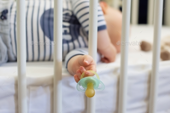 Little baby boy who is peacefully sleeping in his bed holding pacifier ...