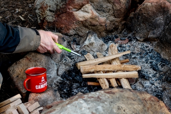 Starting the camp fire with kindling and gas lighter. Log cabin method ...