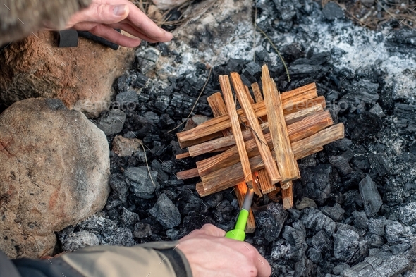 Starting the camp fire with kindling and gas lighter. Log cabin method ...