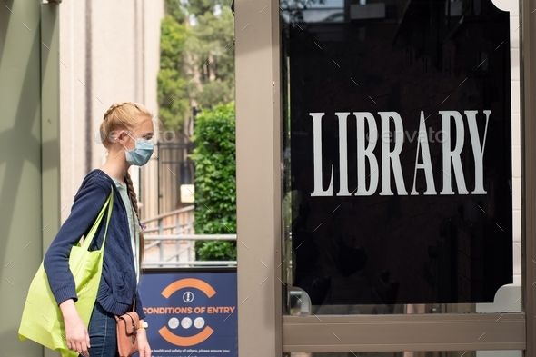 Teenage girl wearing face mask entering the library. Mandatory face ...