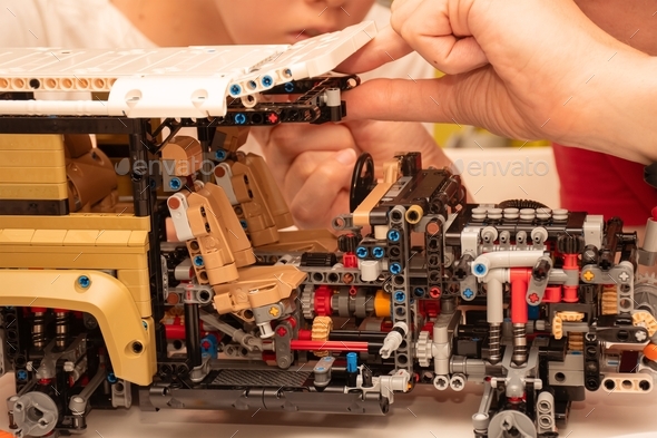 Hands making a complex car vehicle from plastic pieces blocks ...