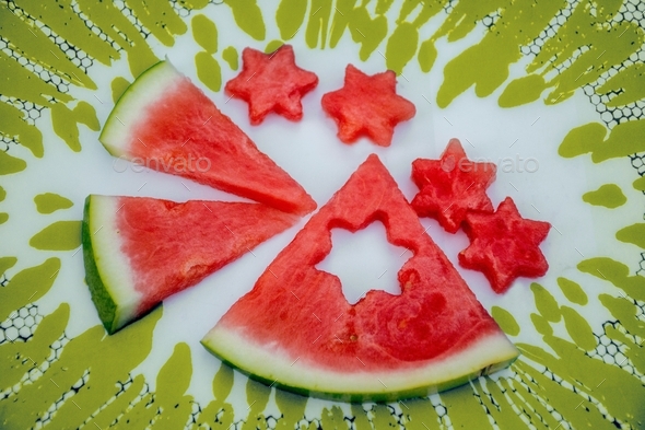 A ripe seedless watermelon on a green background. Star shaped ...