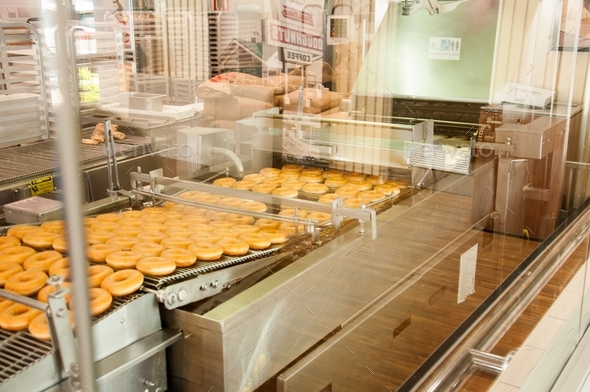 Donuts factory machine. Fresh fried donuts going further to be glazed ...