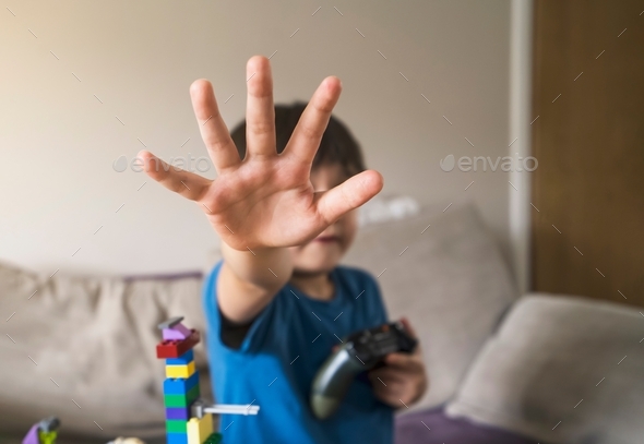 Kid showing stop gestures with his hand while holding video game ...