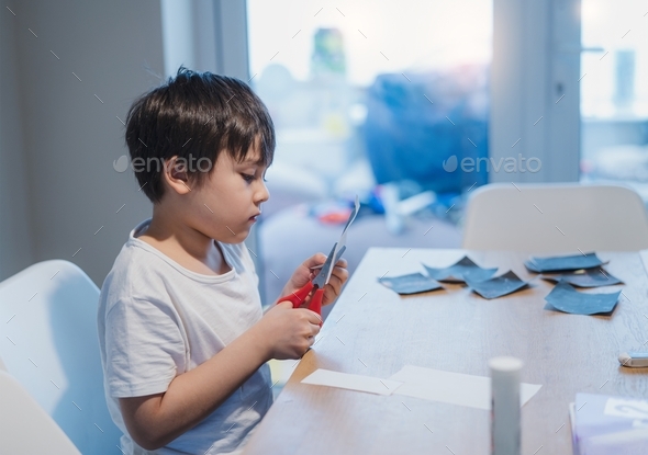 Kid using scissors cutting paper. Child boy making art and craft for ...