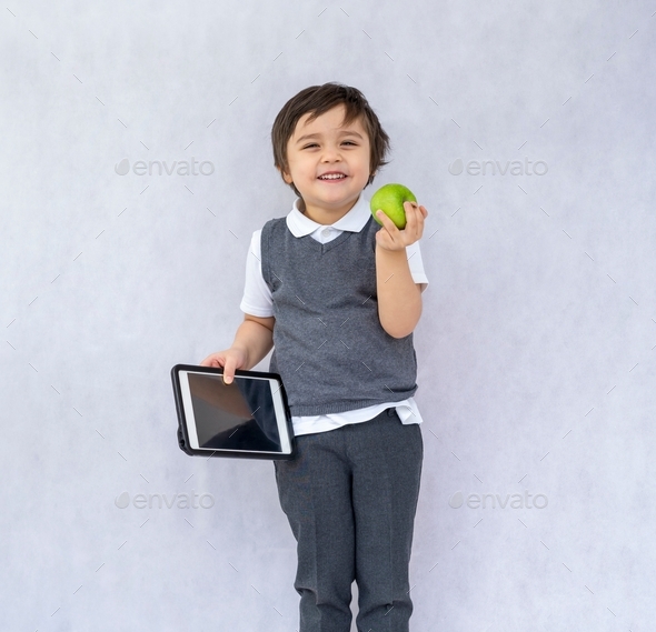 kid holding tablet pc and apple with a happy face.Preschool boy ...