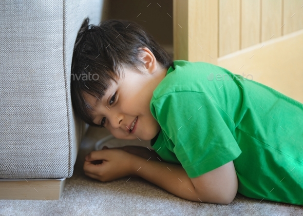 happy kid lying on carpet hiding behide sofa,child playing hide and ...