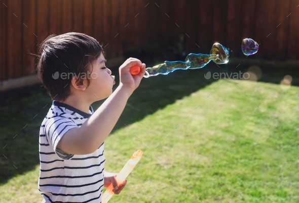 boy blowing soap bubbles in the garden,kid blowing bubble wan playing in the garden on summer ...