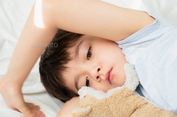 Kid 7 year old lying on bed, Sleepy child waking up the morning in his ...