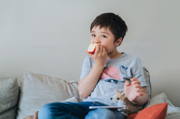 Healhty kid eating an apple while watching TV, Portrait child eating ...