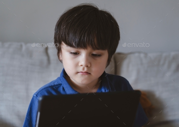 Schoolboy using tablet for his homework, Child boy watching cartoon on ...