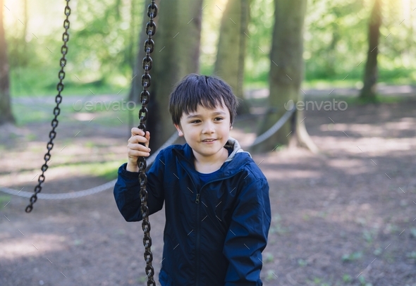 kid holding metal chains in playground, Child enjoying outdoors ...