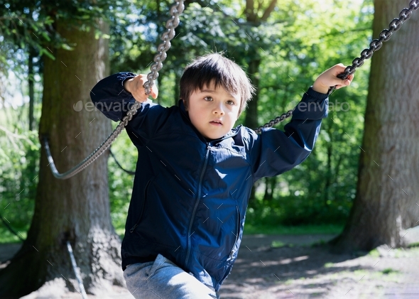 kid holding metal chains in playground,Child enjoying activity in a ...