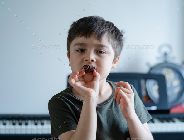 Cute boy eating chocolate cake, Happy Child looking at camera while ...