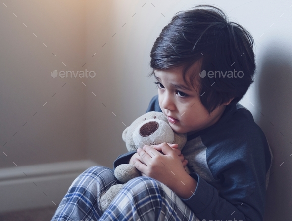 boy sitting on carpet cuddling teddy bear with scared face,Toddler boy ...