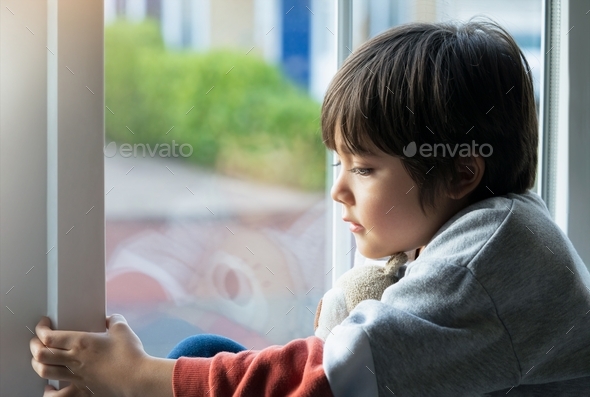 Happy kid sitting next to window playing with teddy bear, Cute boy ...
