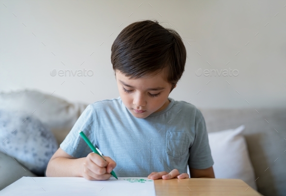 Schoolboy using green colour pen drawing on white paper sheet, Young ...