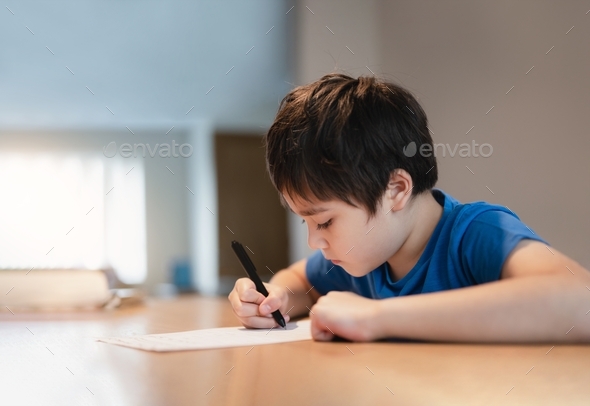 School kid using black pen drawing or writing the letter on paper ...