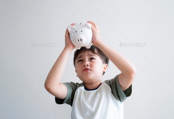 Kid boy with empty piggy bank,Isolated Child looking at underneath ...