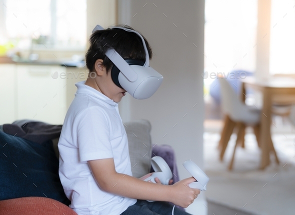 Young kid wearing virtual reality goggles. Emotional Boy playing video ...
