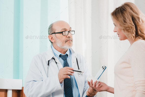 side view of senior doctor and female patient with medicines in hand in ...