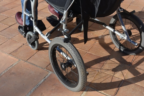 Unidentifiable disabled person in wheelchair, outdoors, wheels and ...