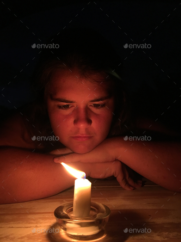 Mental Health. Teenage girl, looking sad, watching a candle flicker ...