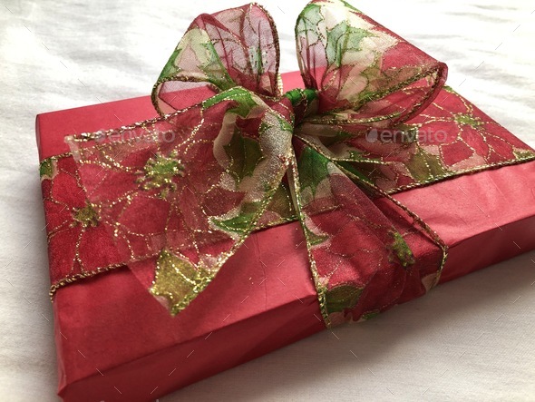 Christmas gift wrapped in red paper decorated with a ribbon tied in a ...