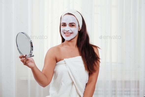 Smiling millenial woman in beauty studio, white moisturizing face skin ...