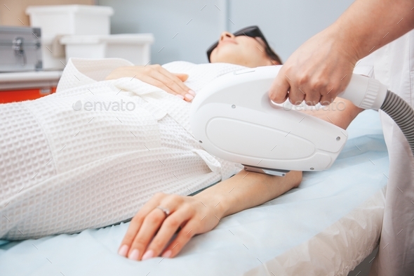 Young woman in beauty salon on arm laser hair epilation procedure Stock ...