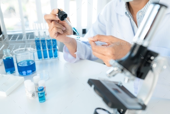 Scientist woman holding dropper to dropping solution sample on the ...