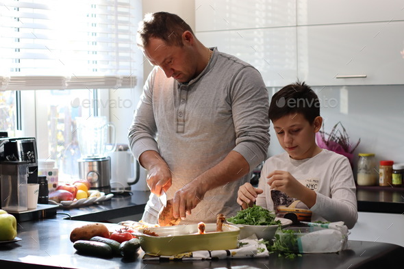 Father and son cooking in the kitchen. Boy helping dad cook. Stock ...