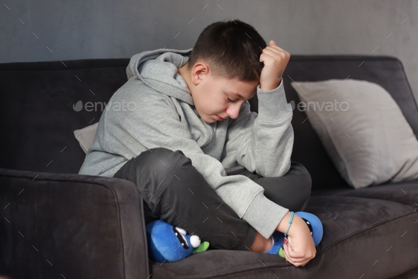 Stressed boy, depression in a child. Boy seating on the couch and ...