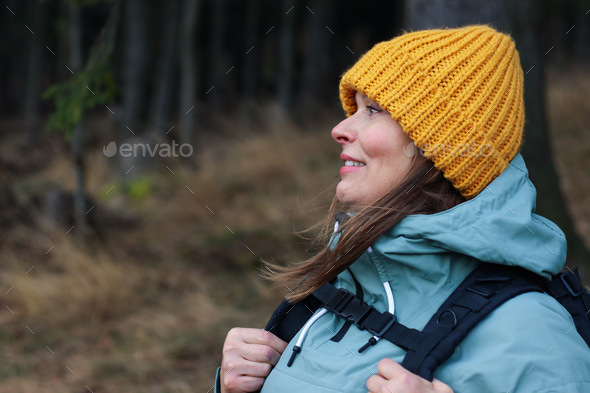 Profile of a woman while hiking in the woods.Smiling face, pop of color ...