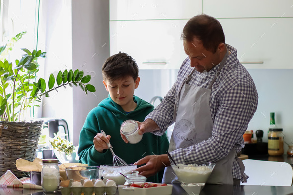 Father and son baking in the kitchen. Boy helping dad baking cake ...