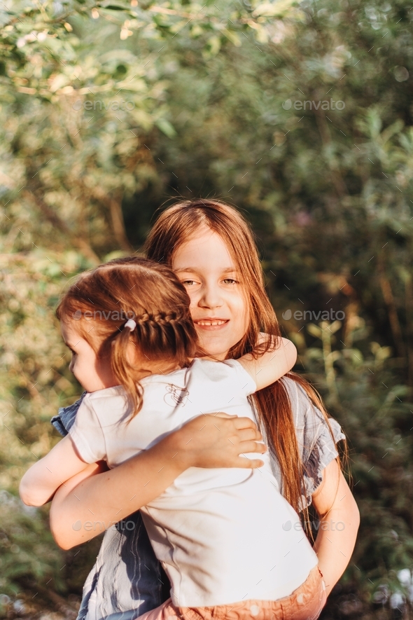 Two little girls hugging in summer park. Stock Photo by akimovanadezhda