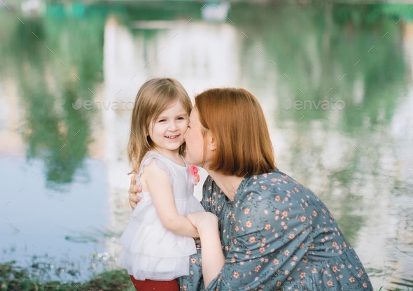 Young mother hugging her little daughter. Stock Photo by akimovanadezhda