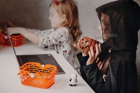 Kids wear Halloween costumes sitting at table with notebook, connecting ...