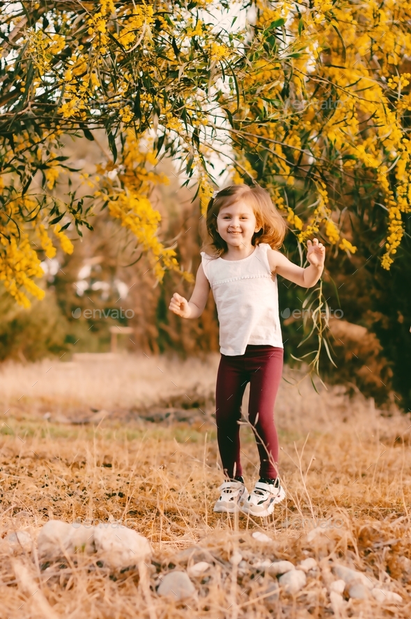 Toddler girl jumping in spring park with blooming trees. Kids outdoor ...