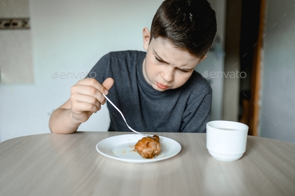 sad boy eats in the kitchen. fried chicken . doesn't want to eat Stock ...