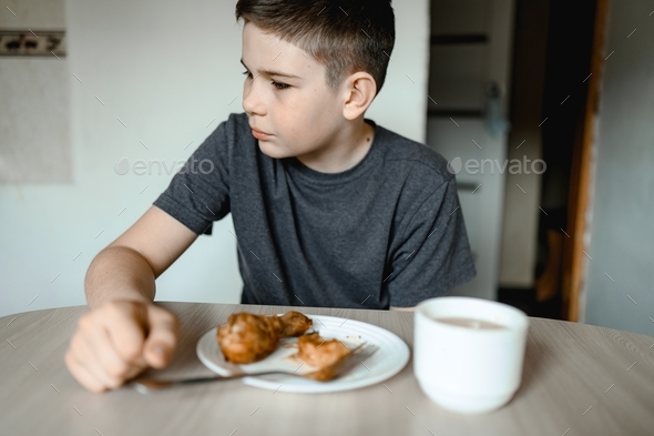 sad boy eats in the kitchen. fried chicken . doesn't want to eat Stock ...