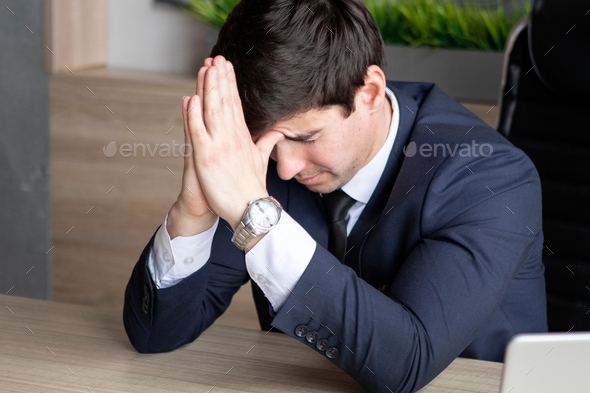 Business man in dark blue suit working at the office. Think and solve ...