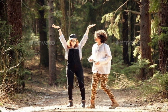 ↟ Two young girls are having fun in the forest. They dance and laugh ...