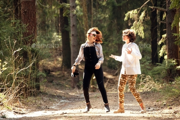 Two young girls are having fun in the forest. They dance and laugh ...
