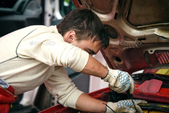 ↟ Professional car mechanic working in an automobile workshop near a ...