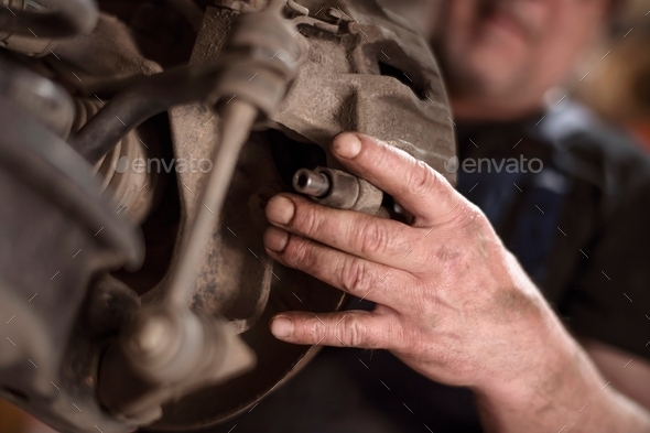 ↟ Professional car mechanic working in an automobile workshop near a ...