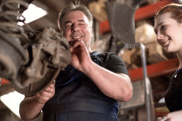 ↟ Professional car mechanic and his young student work in an automobile ...